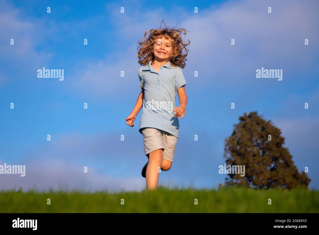 Child run in park outdoor. Spring kid walk on grass. Summer boy ...