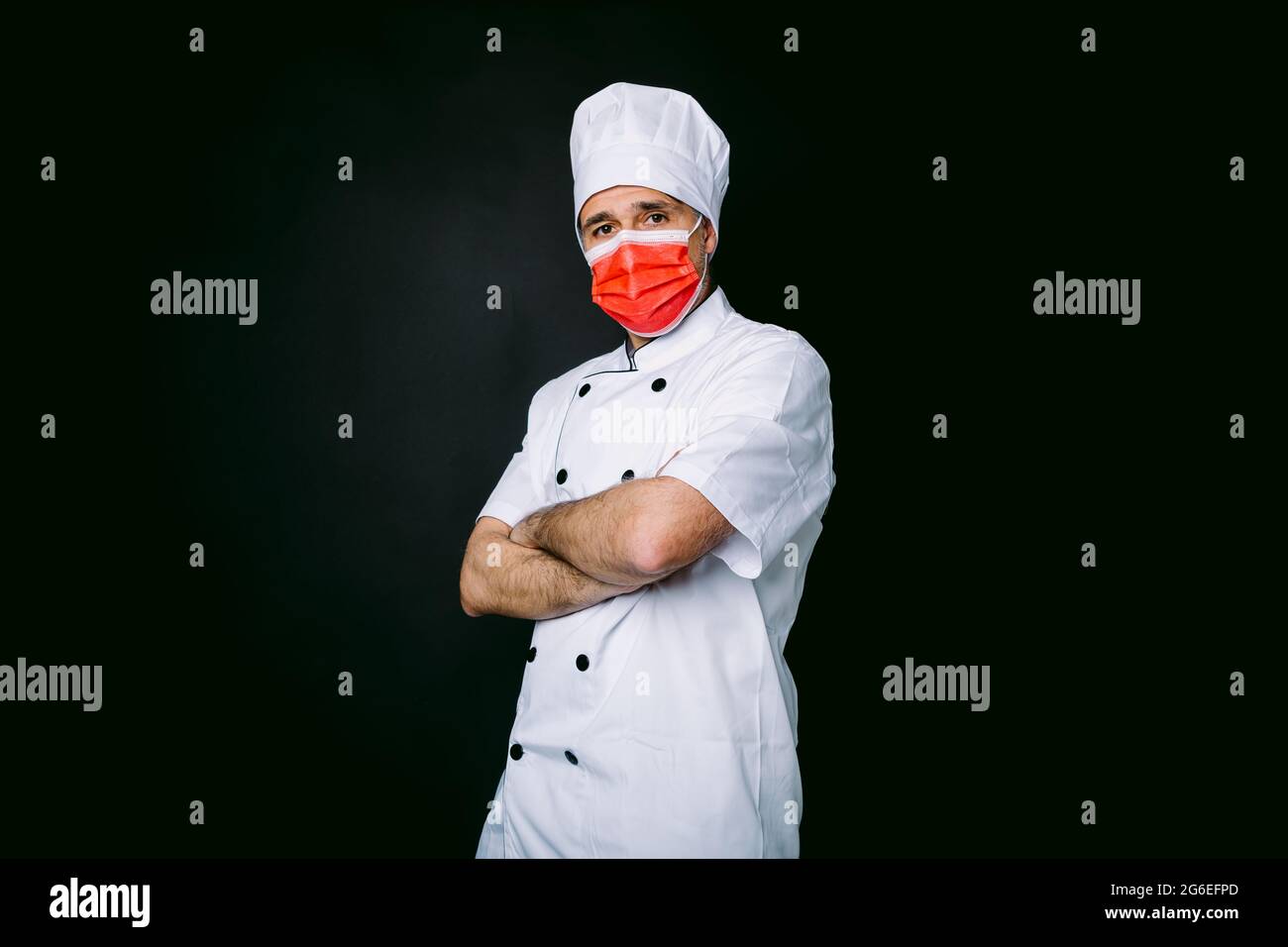 Chef cook wearing cooking jacket and hat, with a red mask, arms crossed ...