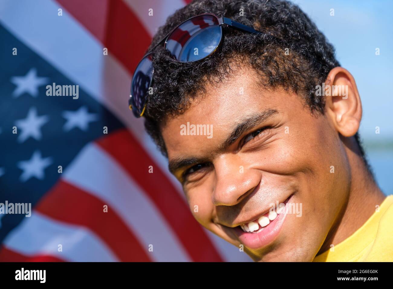 Portrait of smiling African American man standing on American flag ...