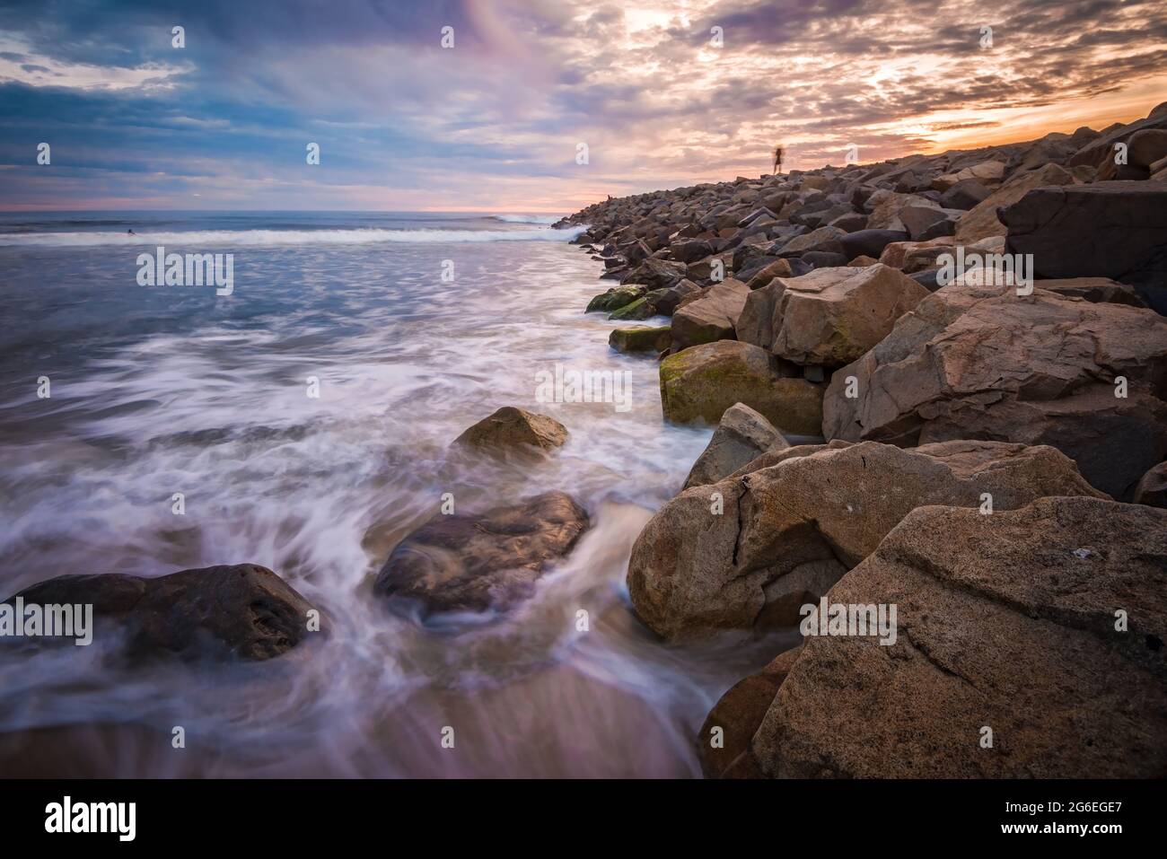 Long exposure surf along a beach jetty at sunset Stock Photo - Alamy