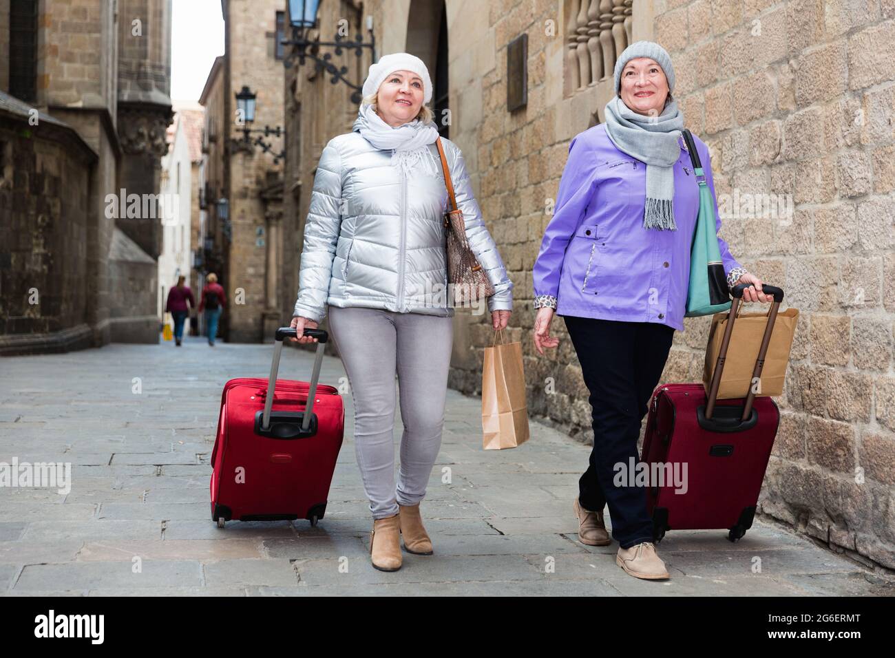 Elderly women strolling with luggage along city street Stock Photo - Alamy