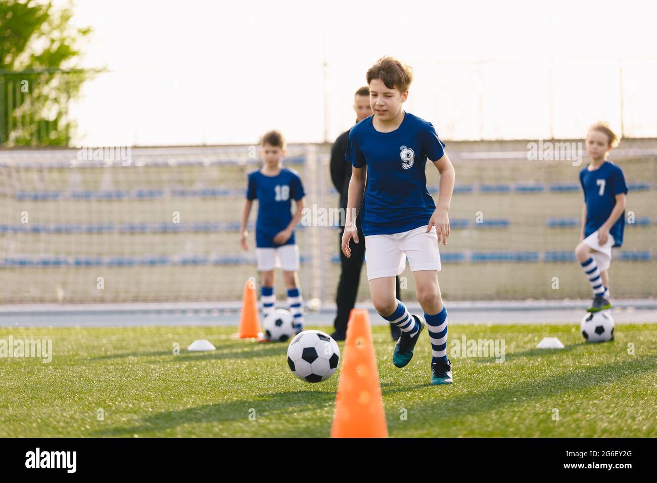 Happy boys practicing football with coach on a sunny day. Group of ...