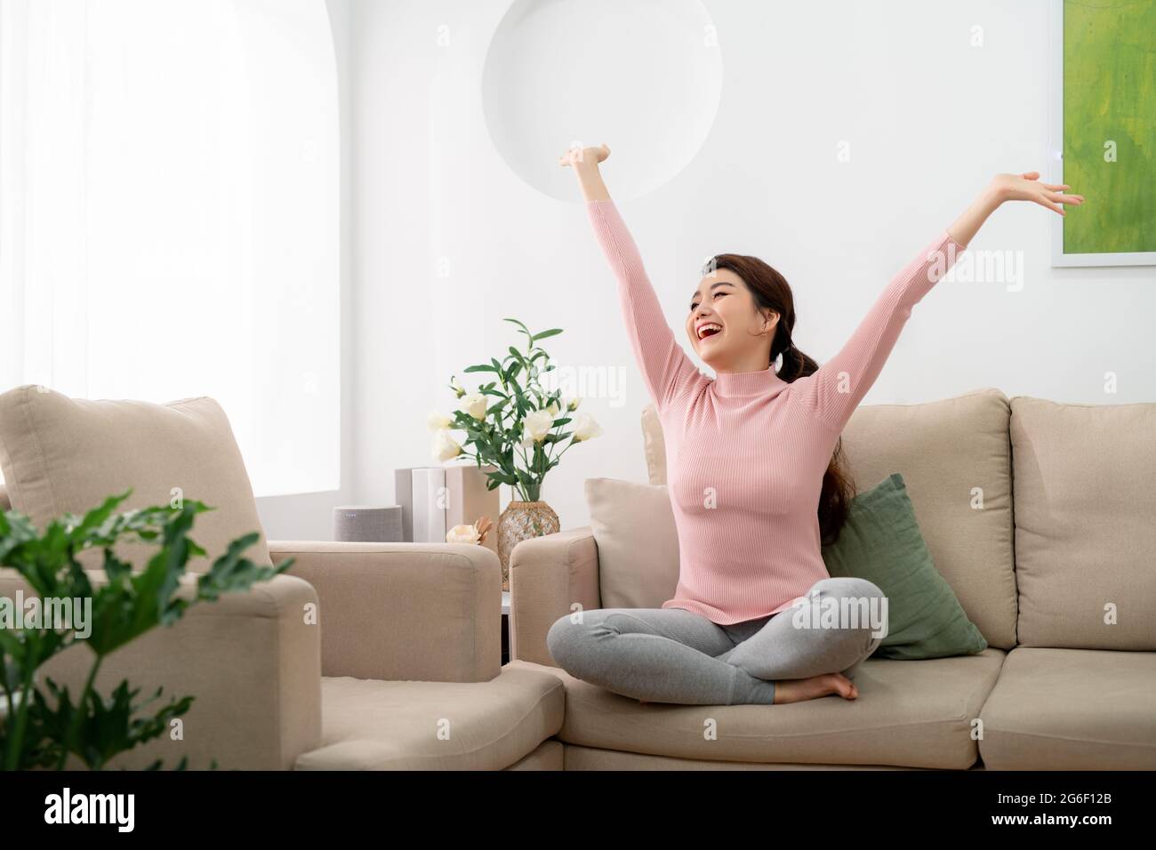 young woman feel carefree and stretch arm to take a deep breath at home ...