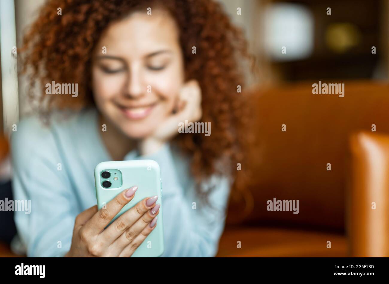 Selective focus at the trendy smartphone in hand of attractive red ...