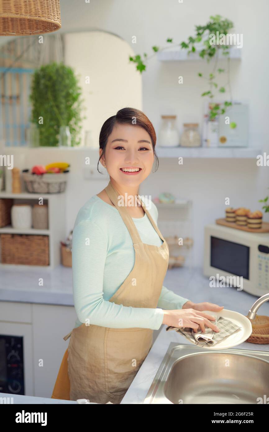 Beautiful young woman is looking at camera and smiling while washing ...