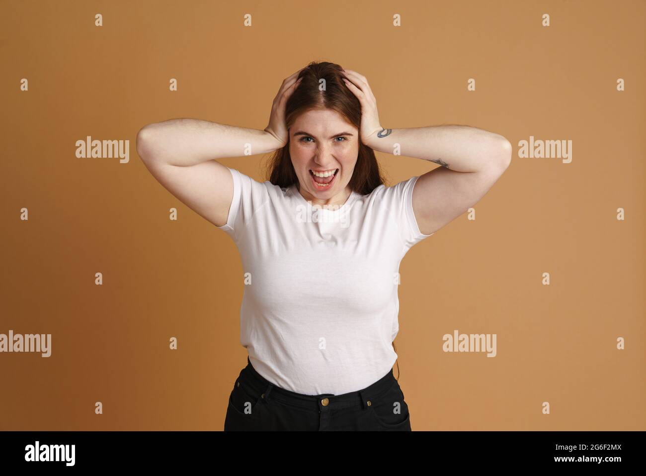 Young irritated woman screaming while holding her head isolated over ...