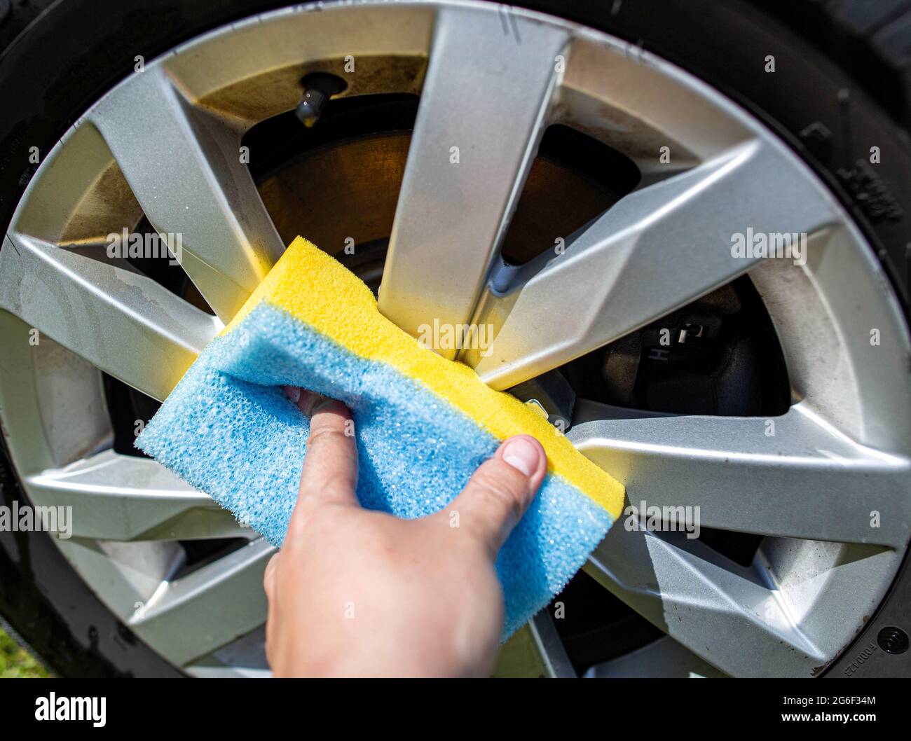 Hand washing car rims with a sponge with car shampoo for cleaning dirt ...