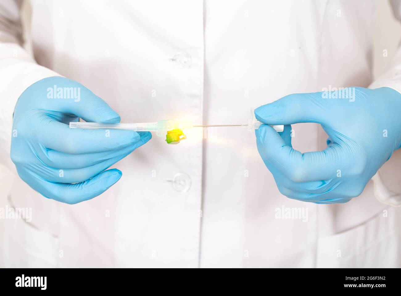 A doctor in medical gloves holds a medical cannula for plastic surgery ...