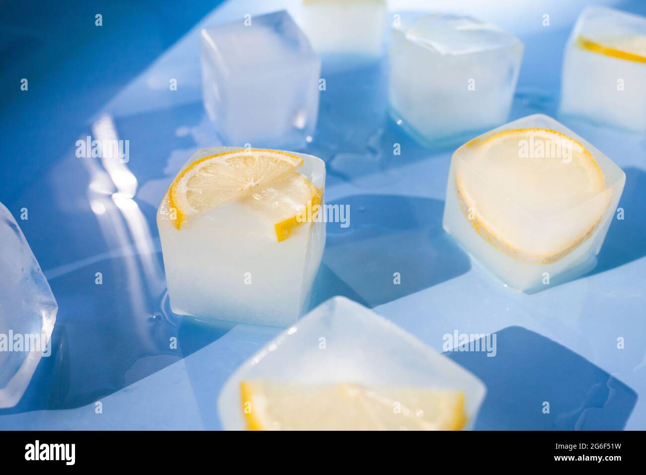 Modern composition of the frozen slices of lemon and ice cubes on a blue background Stock Photo ...