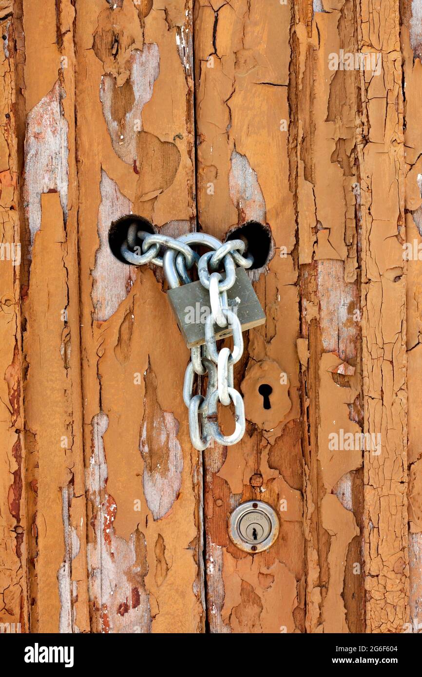 Close up view of a worn textured wooden door detail with chained lock ...