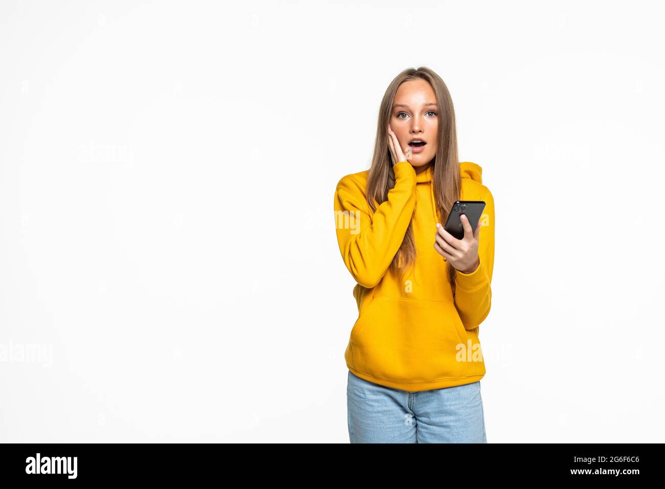Portrait of a shocked woman using mobile phone over white background ...