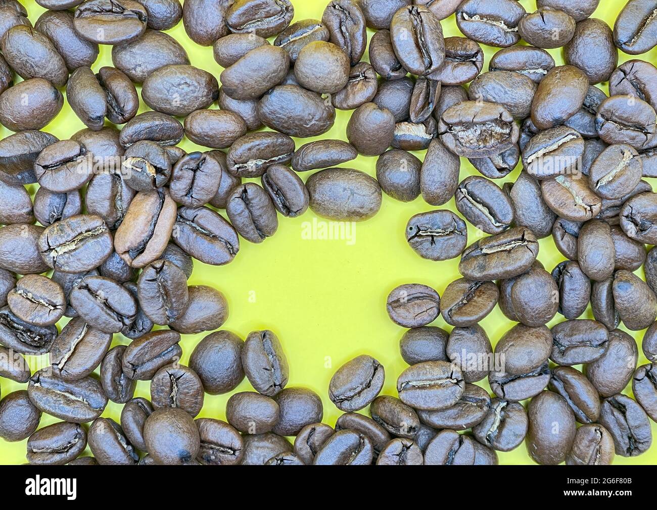 Roast coffee beans on yellow background with round space in the middle ...