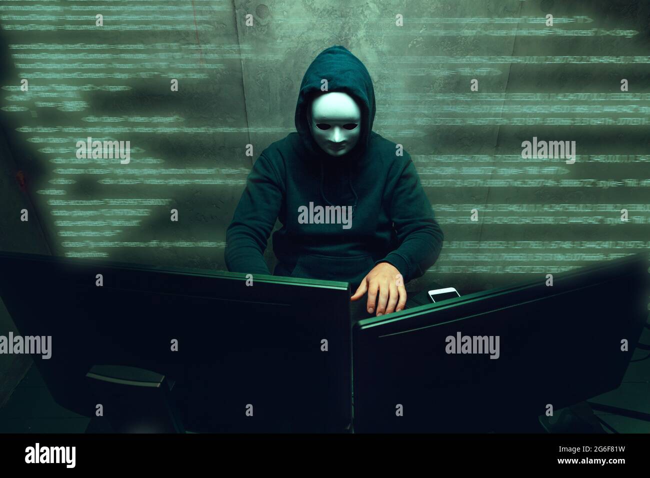 Anonymous hacker wearing face mask working on computer in dark room ...