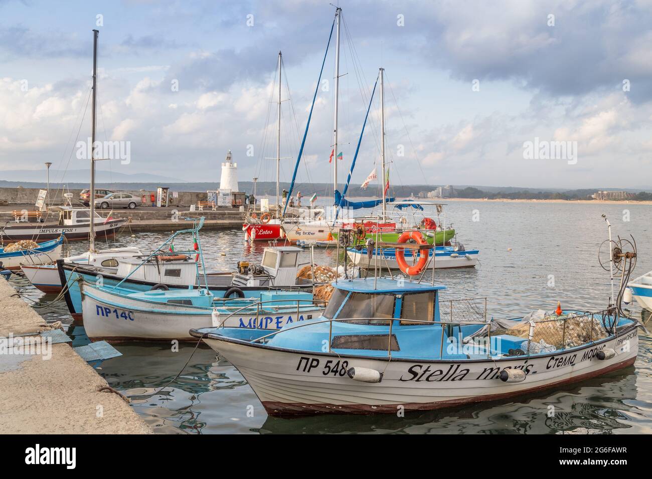 Port - small lighthouse, fishermen, yachts and fishing boats against ...