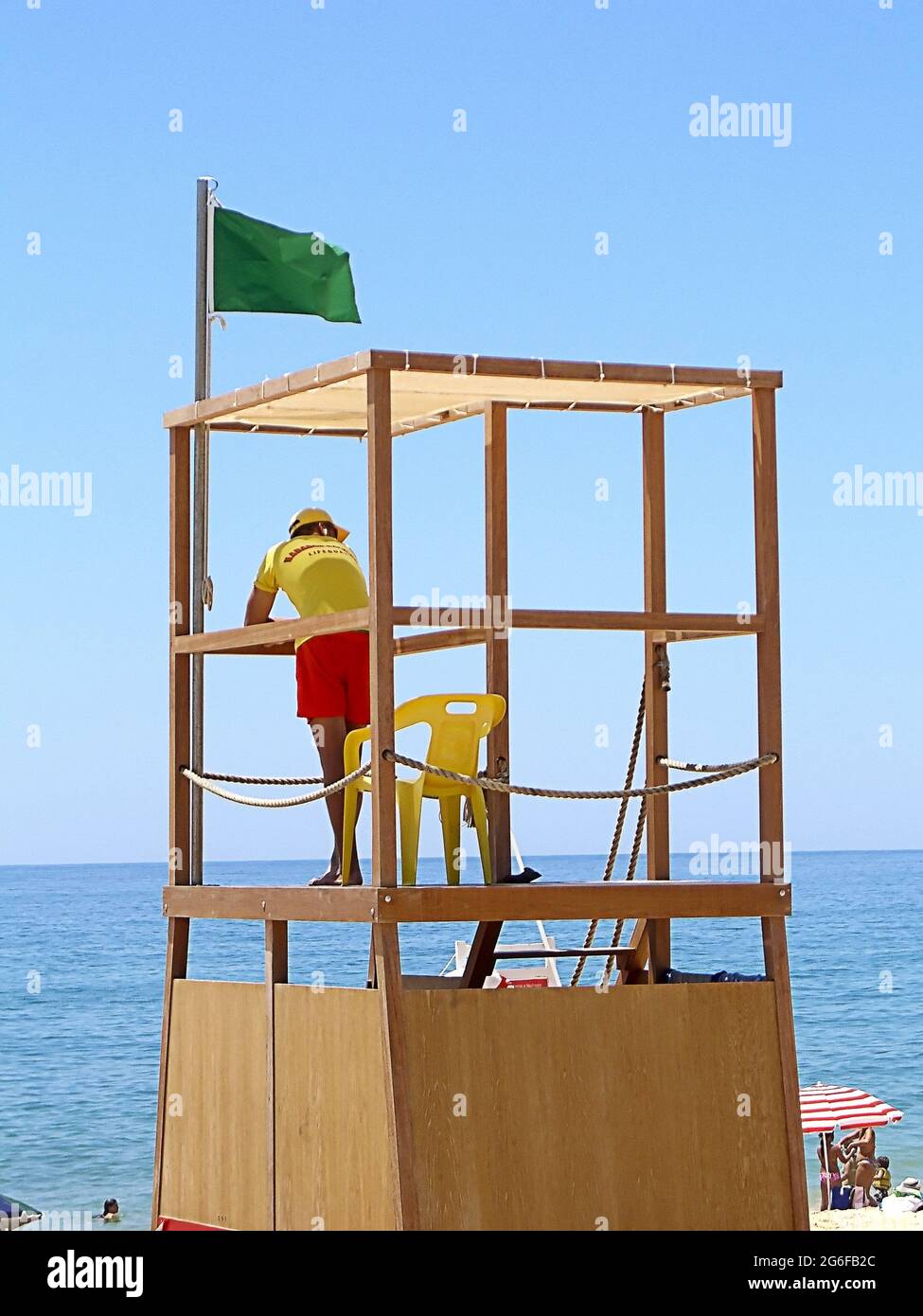 lifeguard on top of a beach watch tower with a green flag Stock Photo ...