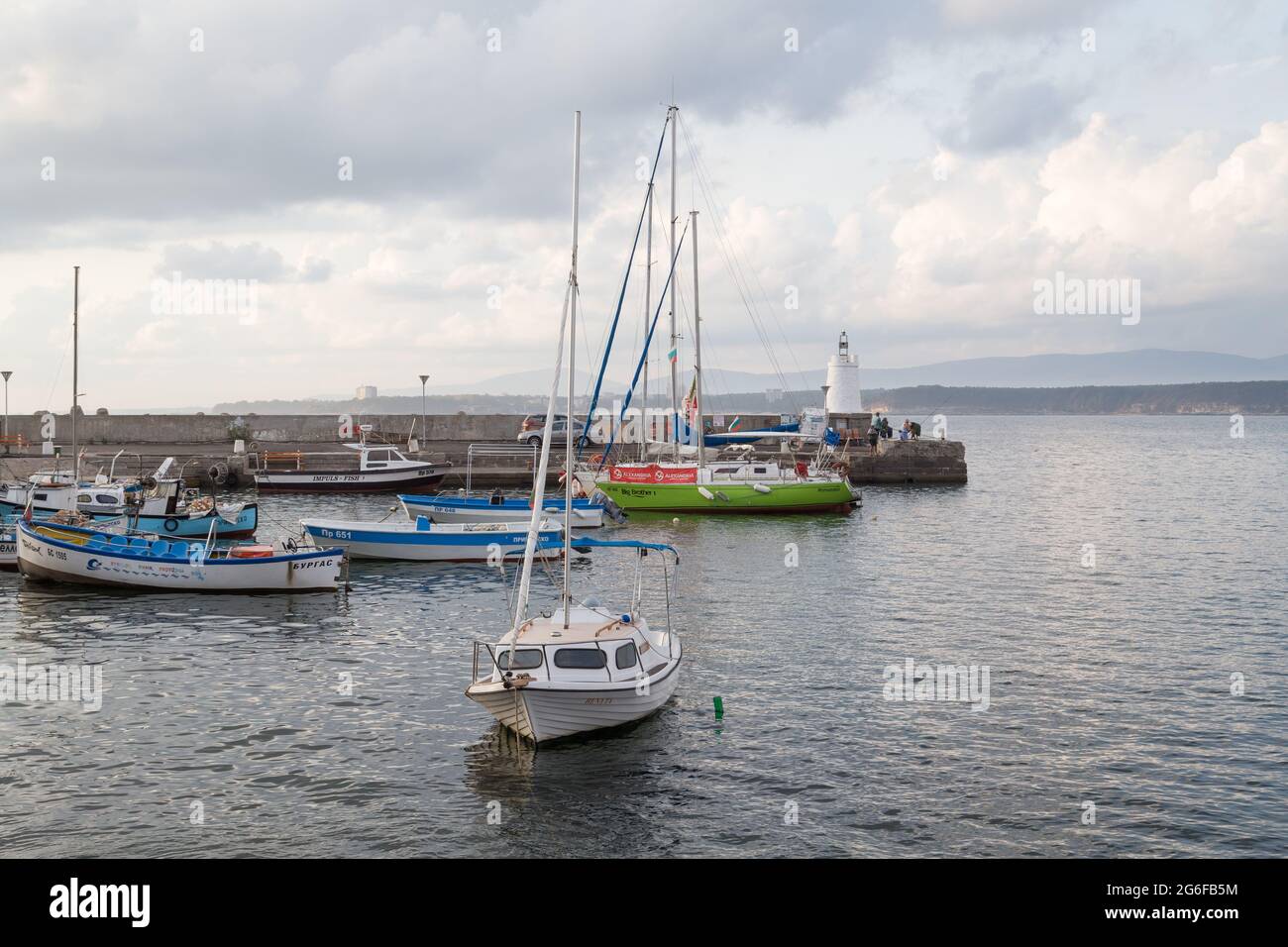 Port - small lighthouse, fishermen, yachts and fishing boats against ...