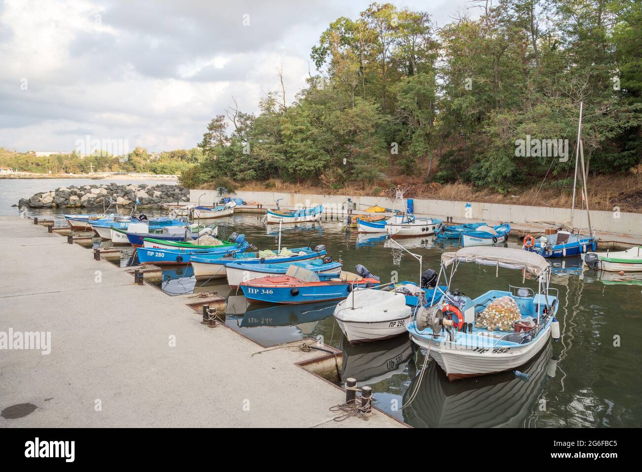 Port - small lighthouse, fishermen, yachts and fishing boats against ...