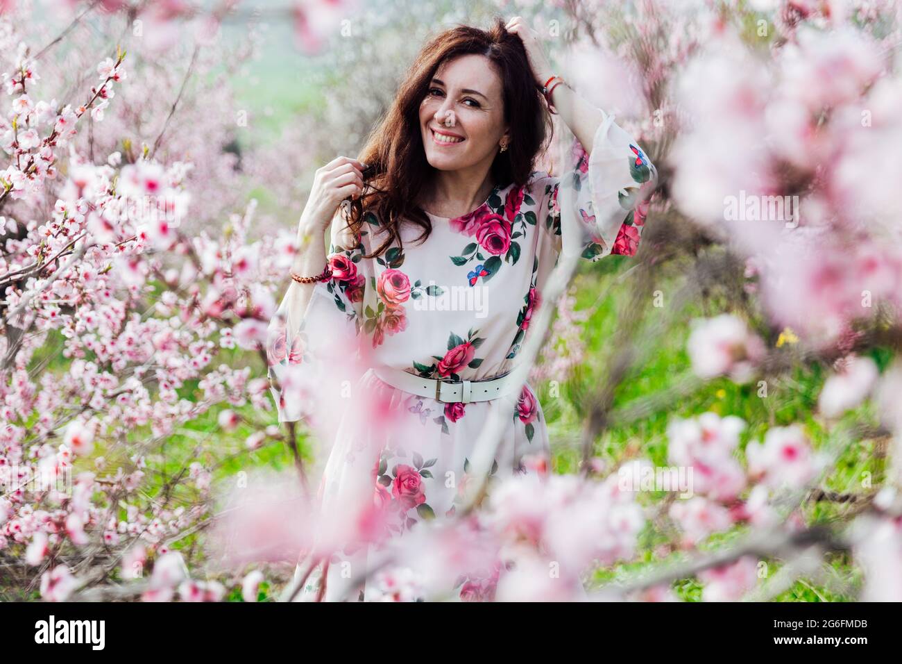 Beautiful woman in a dress with flowers walks through the flowering ...