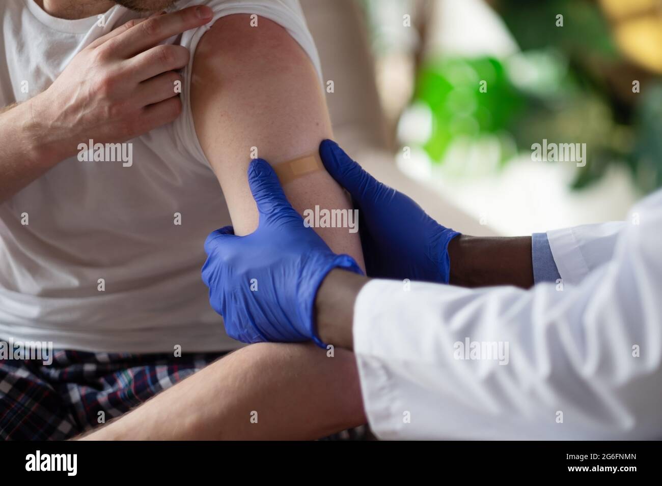 African doctor doing injection of vaccine to male patient Stock Photo ...