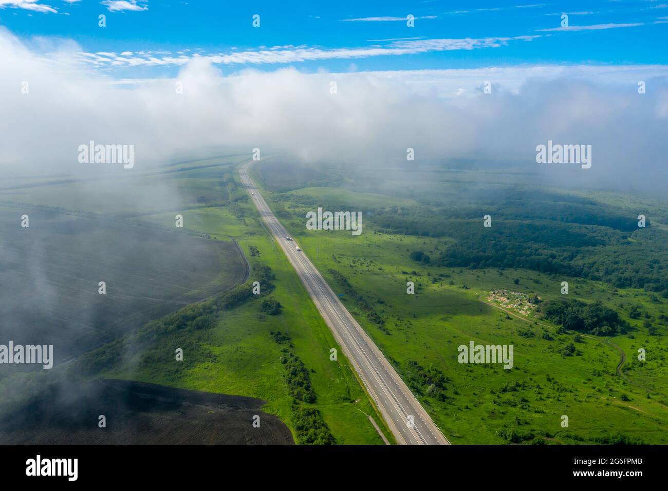 Road with cars, low clouds, shoot from a drone. Beautiful landscape ...