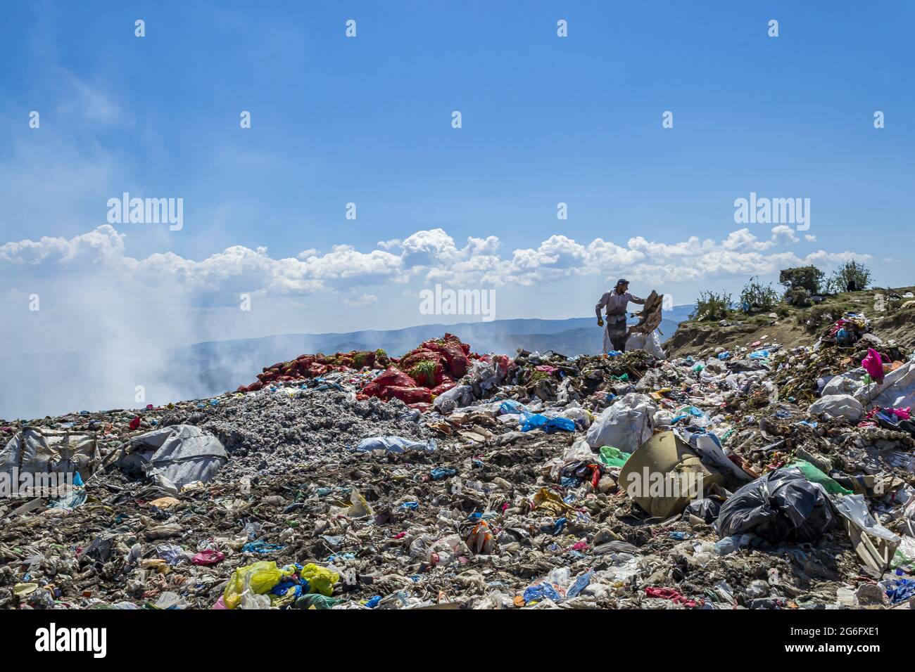 View of garbage field in trash dump or open landfill and a male ...