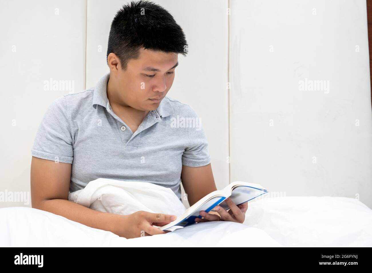 Asian man reading books in bedroom Stock Photo - Alamy