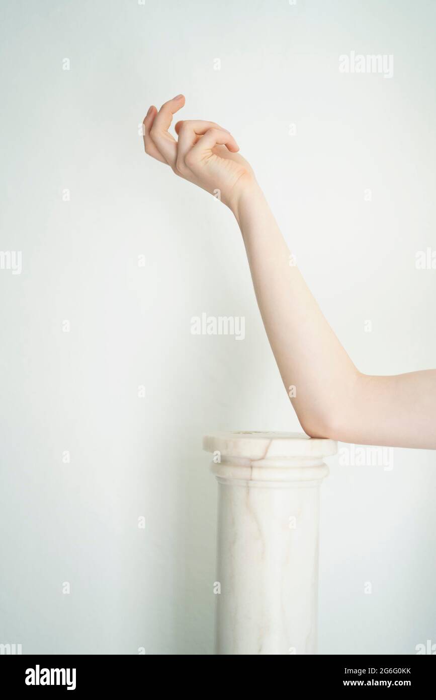 Woman's arm leaning on pillar against white background Stock Photo - Alamy