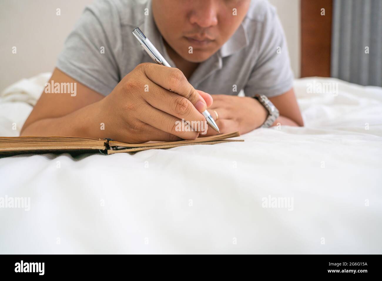 Close up man lie on bed and take notes Stock Photo - Alamy