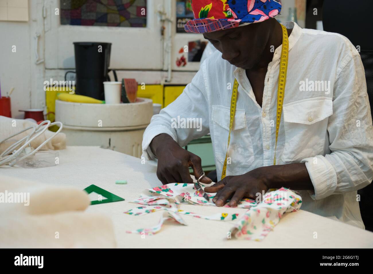 A tailor cutting fabric in his sewing shop. African man working in a ...