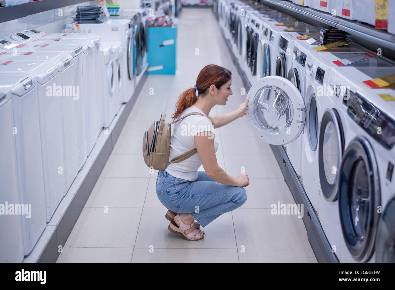 Caucasian woman chooses a washing machine in a home appliances store ...