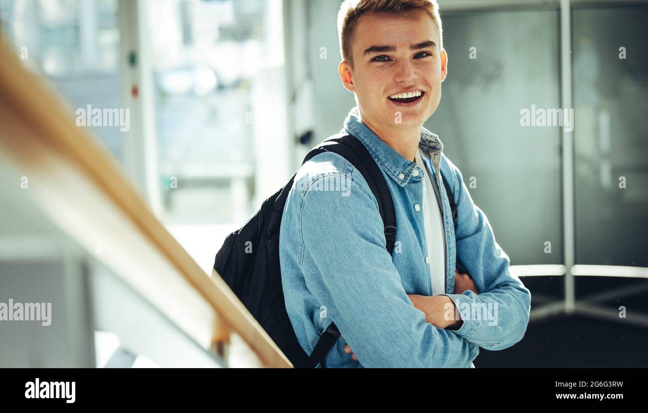 Young man in college campus standing with arms crossed smiling at ...