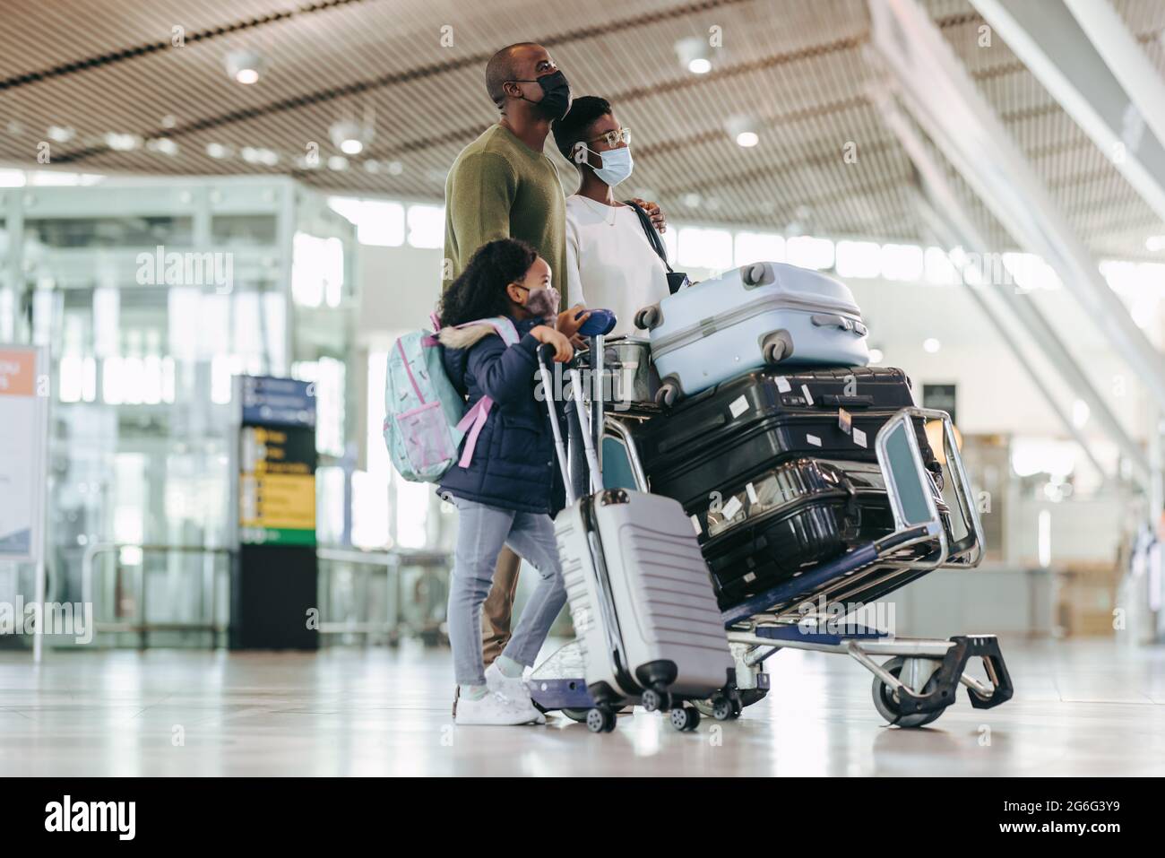 African family standing at airport terminal waiting for flight. Parents ...