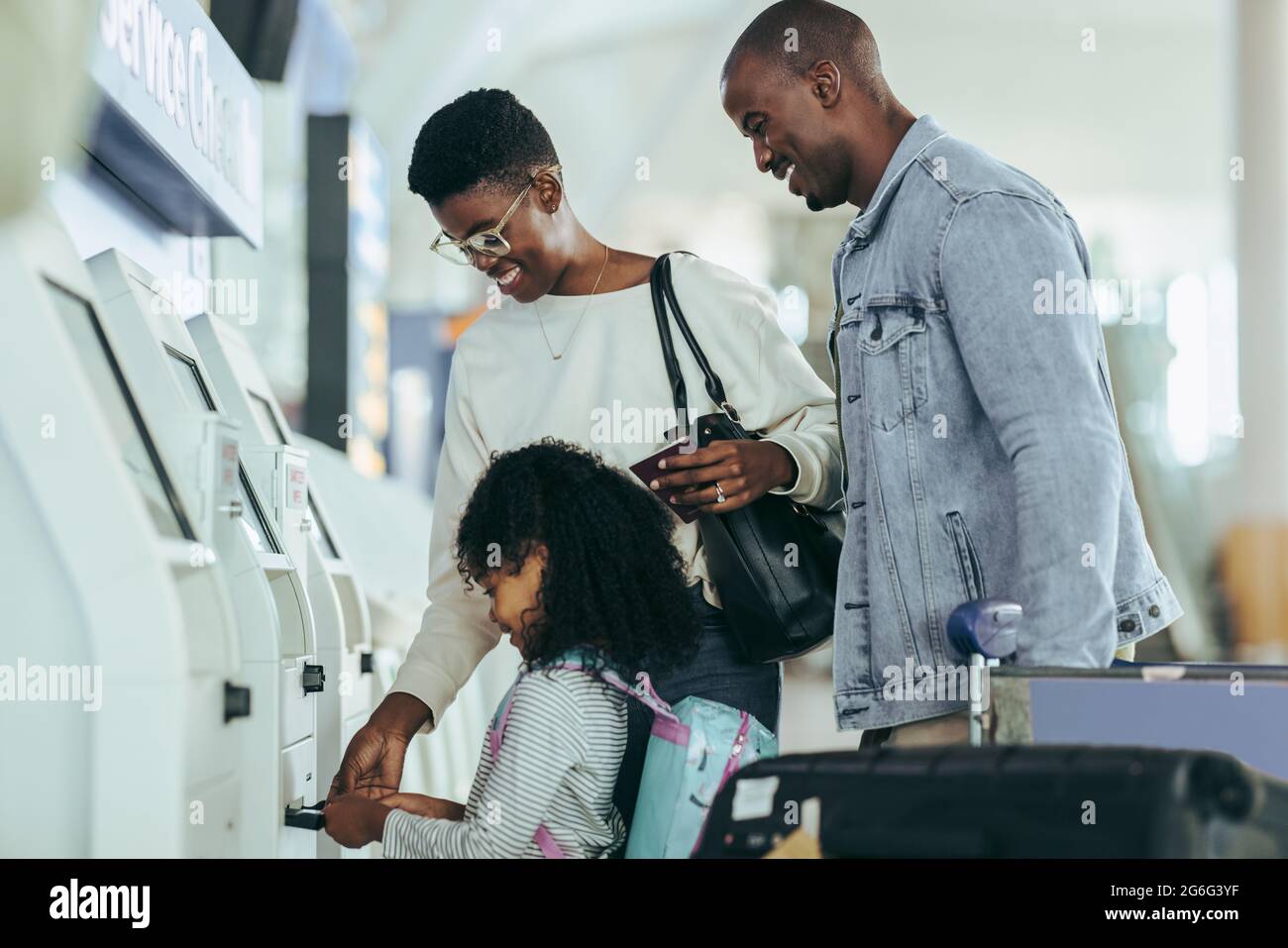 African family taking print of boarding pass from check-in machine at ...