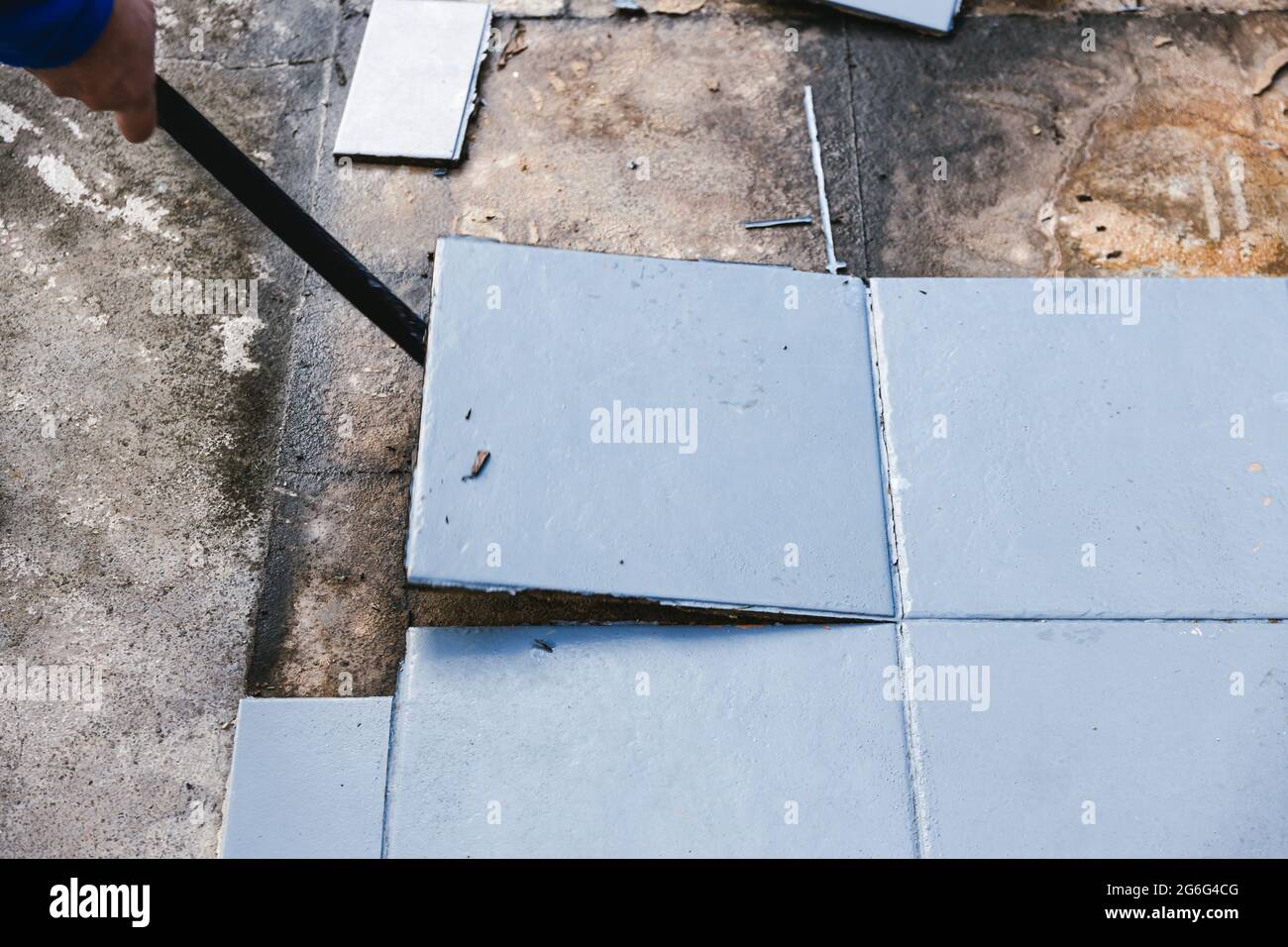 blue outdoor tiles getting ripped up to reveal concrete paving ...