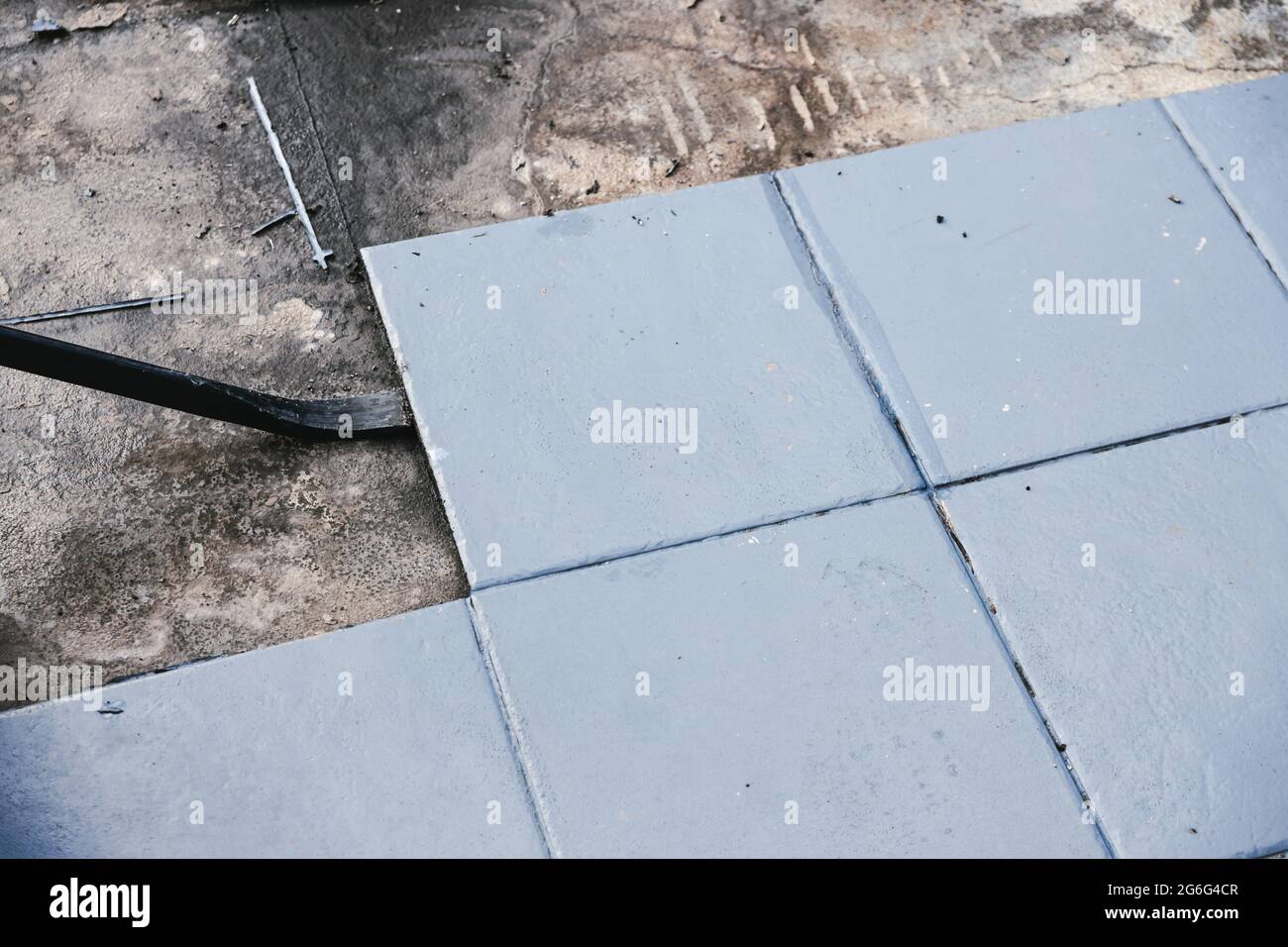 blue outdoor tiles getting ripped up to reveal concrete paving ...