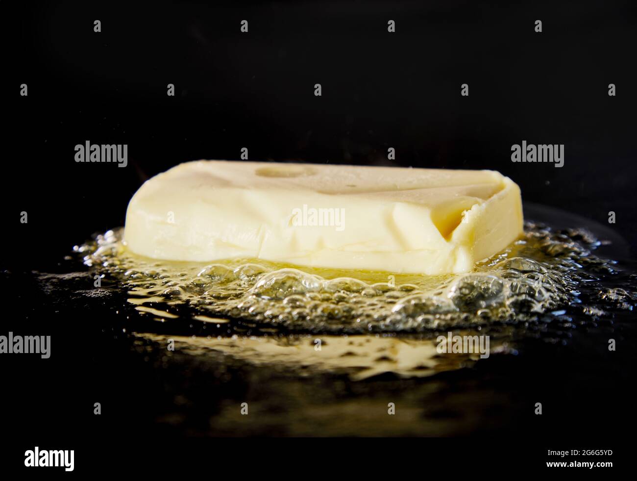 Butter melting on hot surface during cooking process in dark room ...
