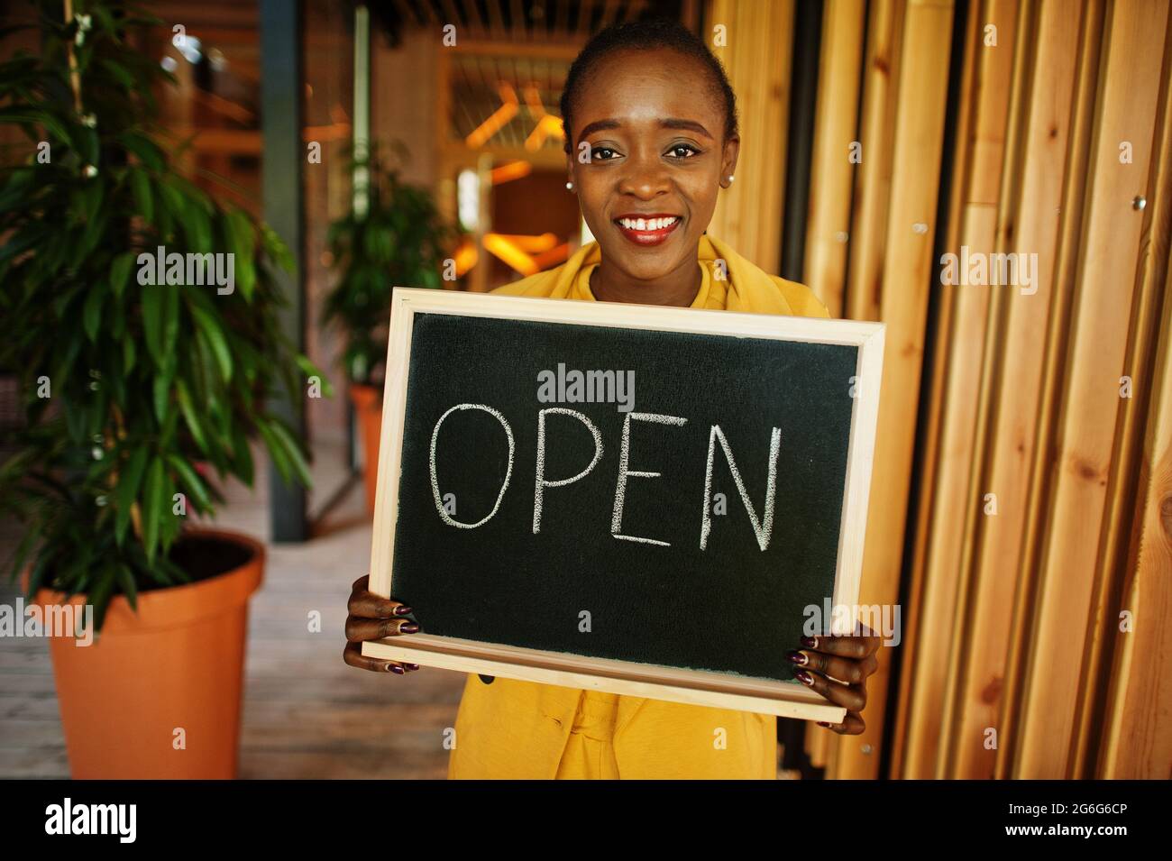 African american woman hold open welcome sign board in modern cafe ...