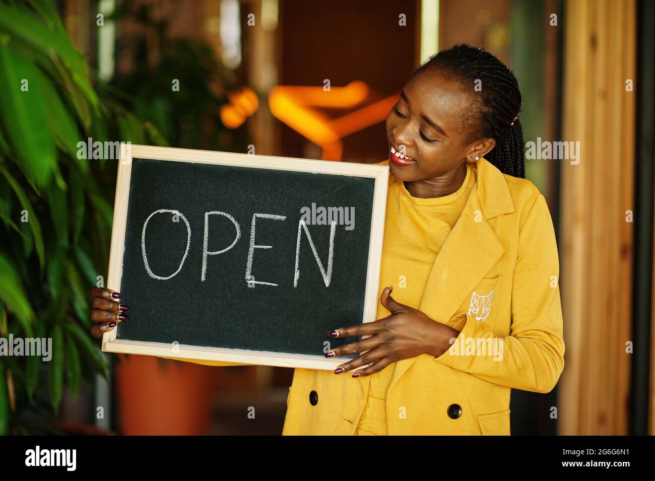 African american woman hold open welcome sign board in modern cafe ...
