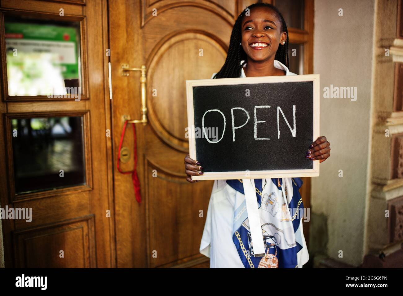 African american woman hold open welcome sign board in modern cafe ...