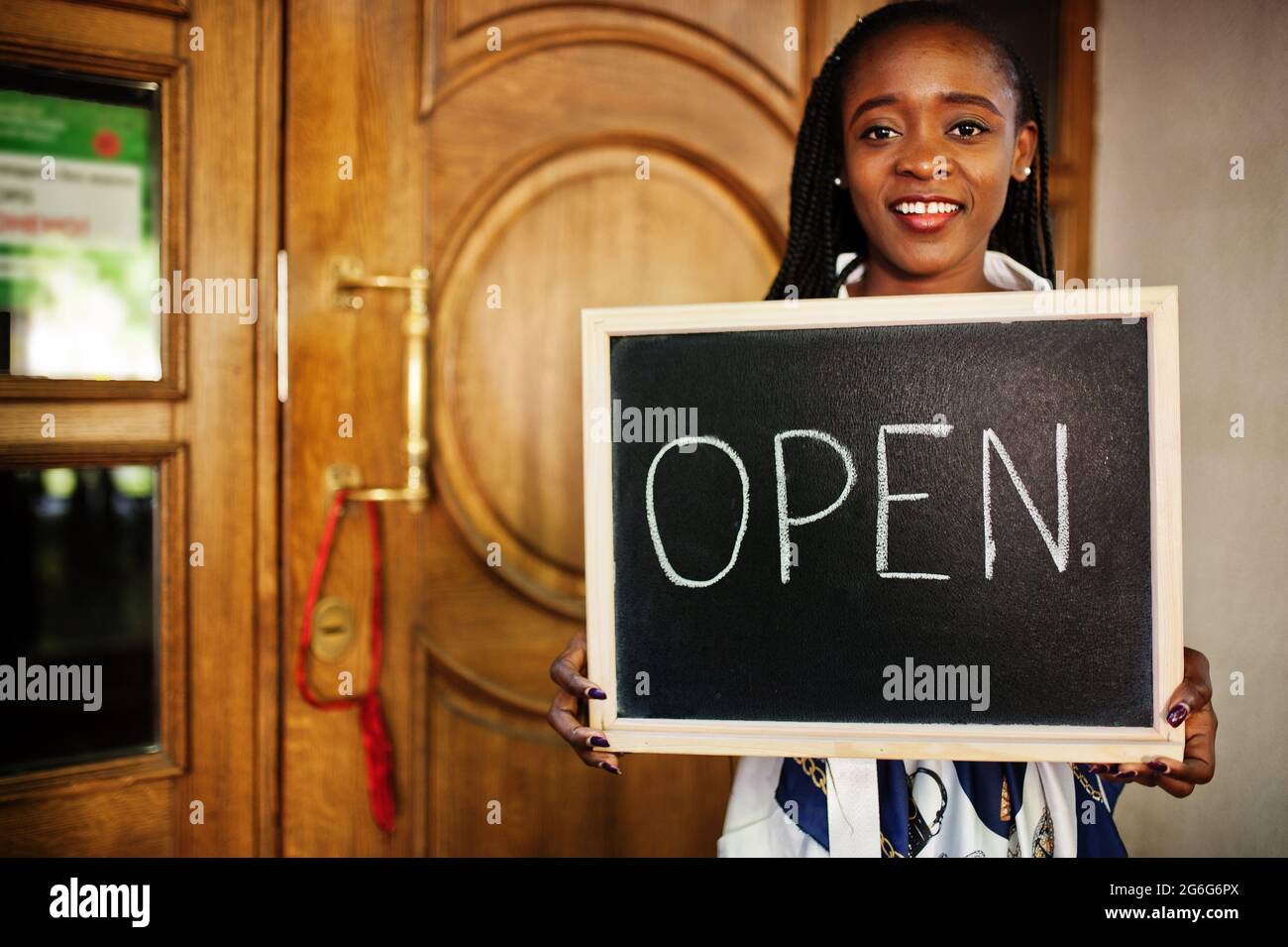African american woman hold open welcome sign board in modern cafe ...