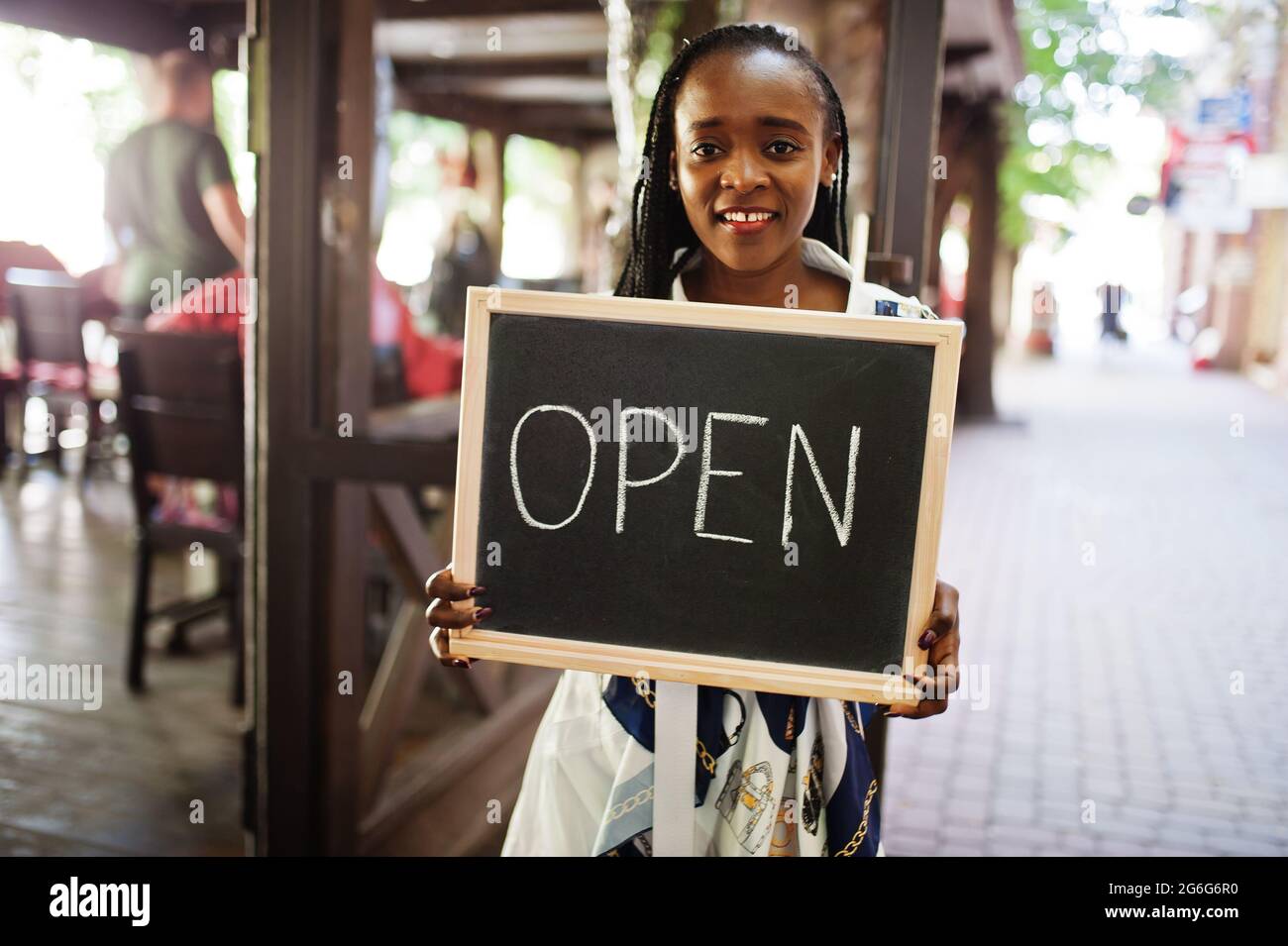 African american woman hold open welcome sign board in modern cafe ...