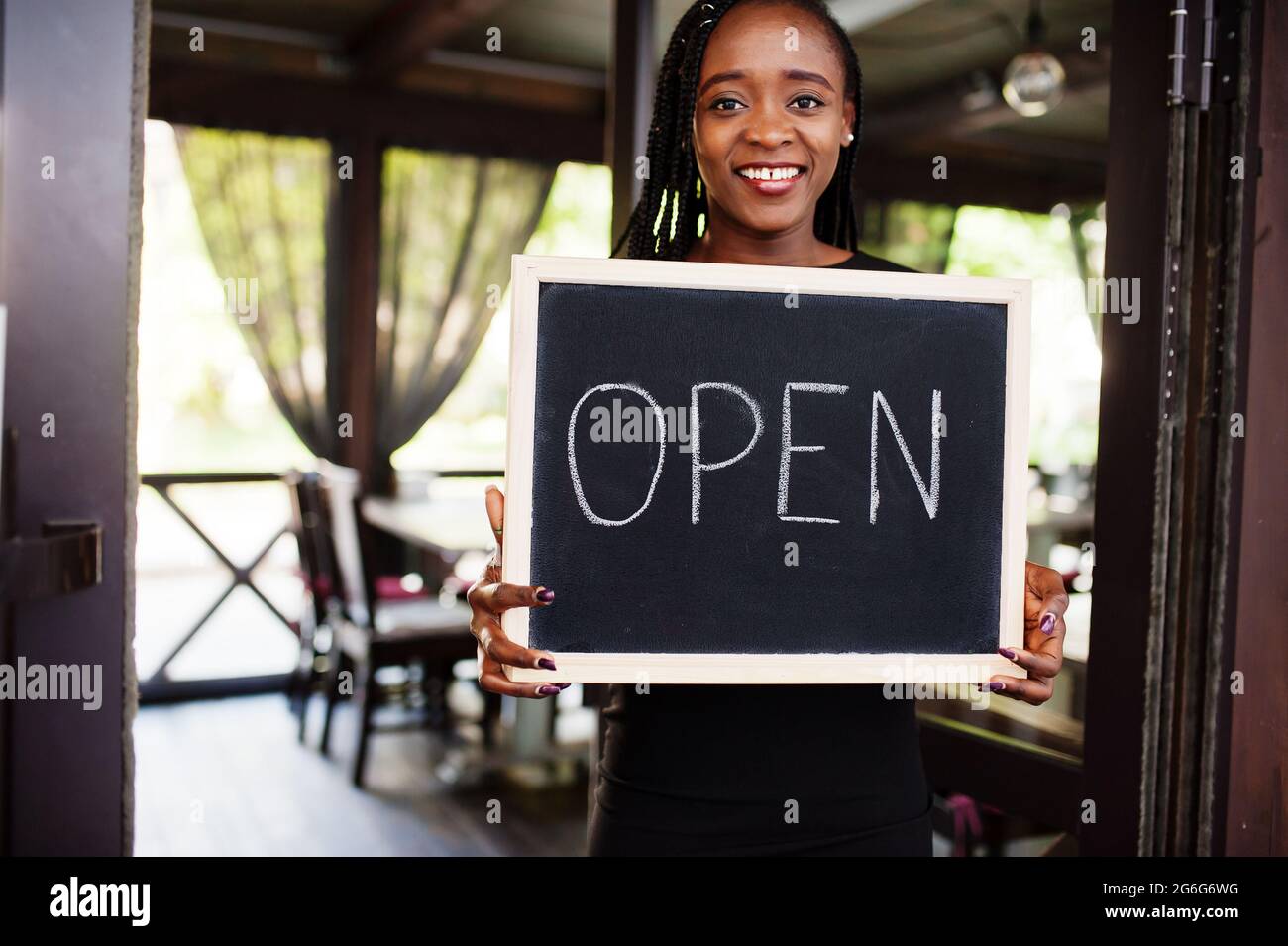African american woman hold open welcome sign board in modern cafe ...