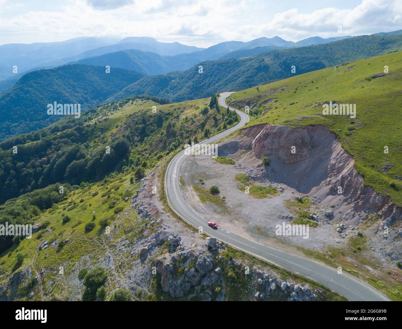 Aerial view, drone chasing fast driving red car on mountain winding ...