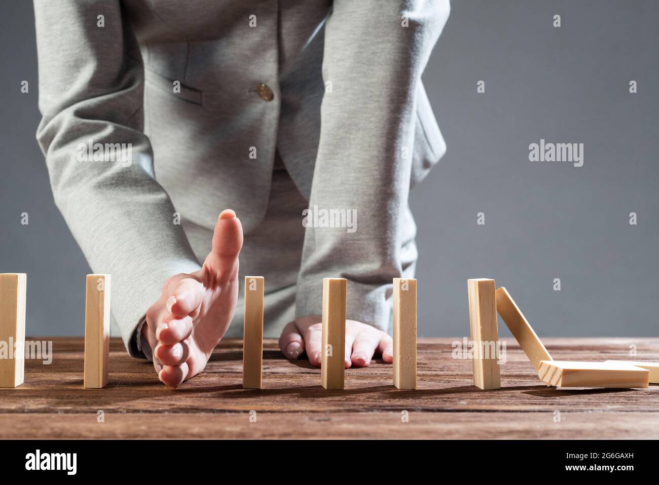 Business woman interrupting domino effect Stock Photo - Alamy