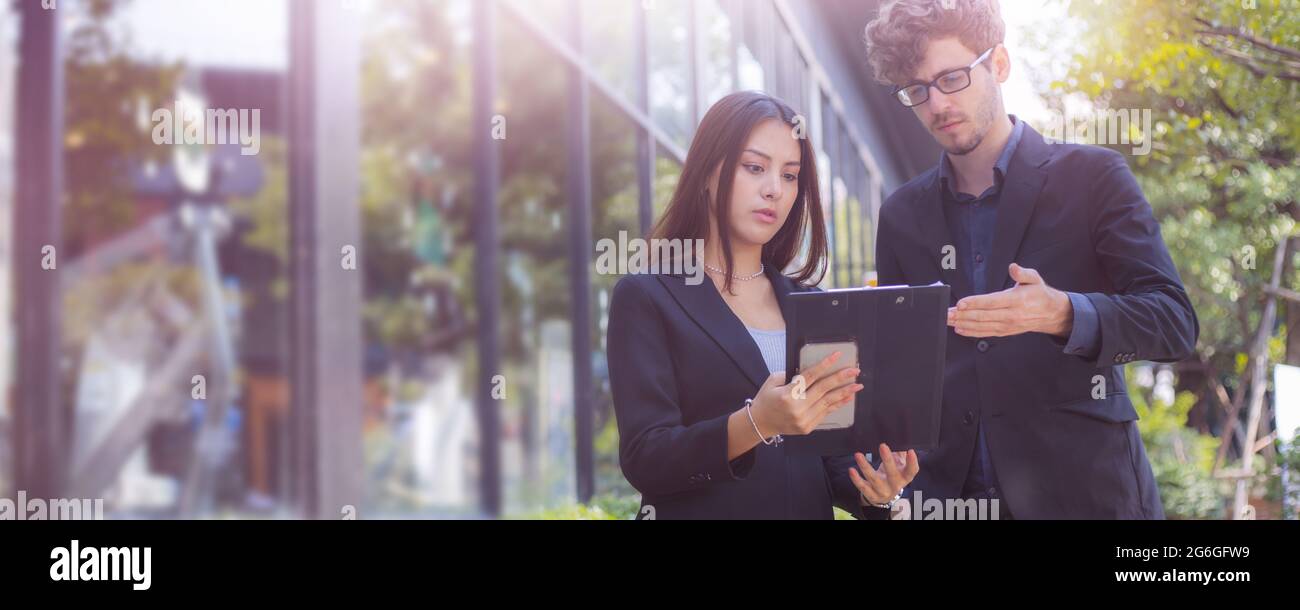 Confidential young business people walk and talk outside office ...