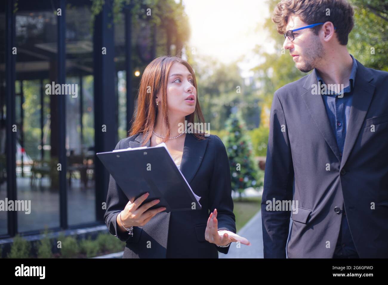 Confidential young business people walk and talk outside office ...