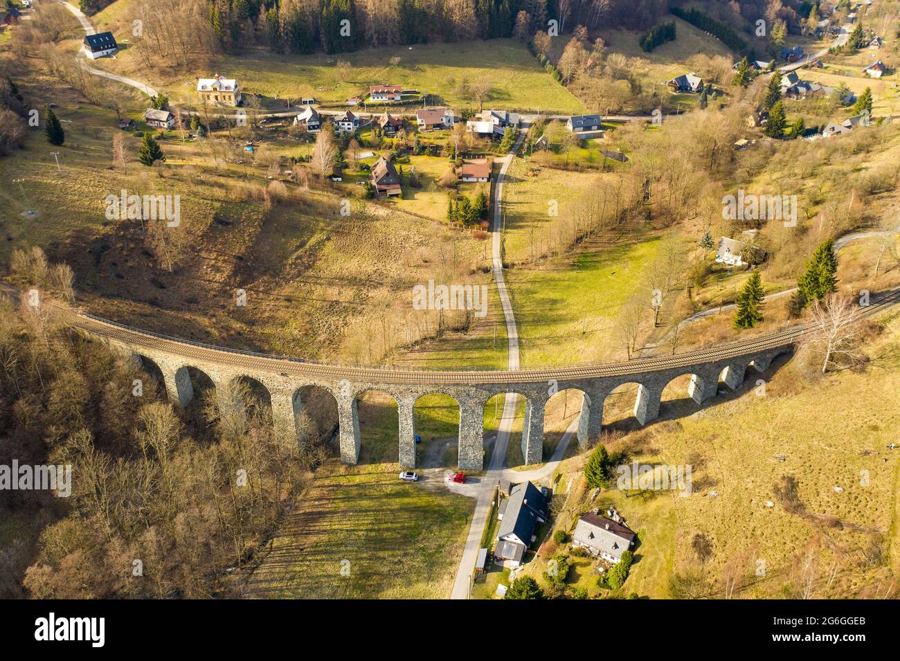 Aerial view of viaduct arch bridge near small village in the forest ...