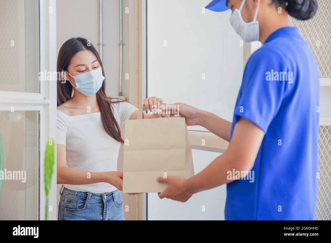 Delivery man wearing mask, deliver bag of food to customer, woman ...
