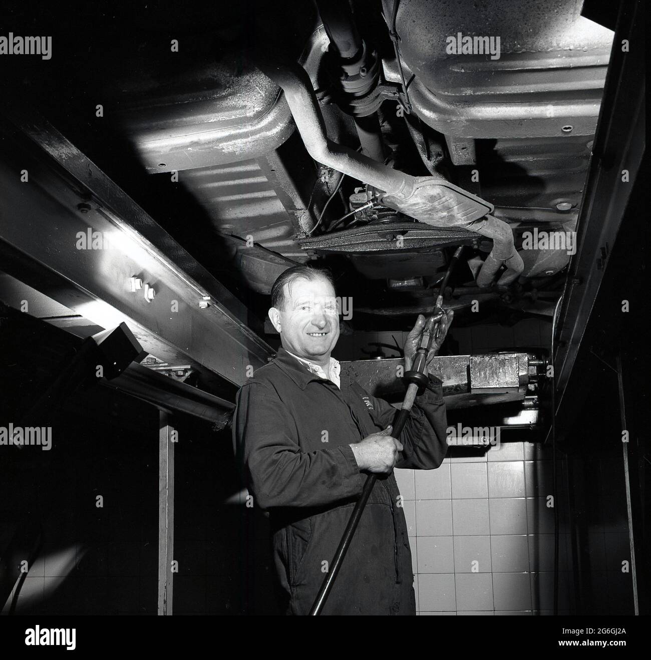 1970s, historical, car servicing, a car mechanic with a pressure value ...