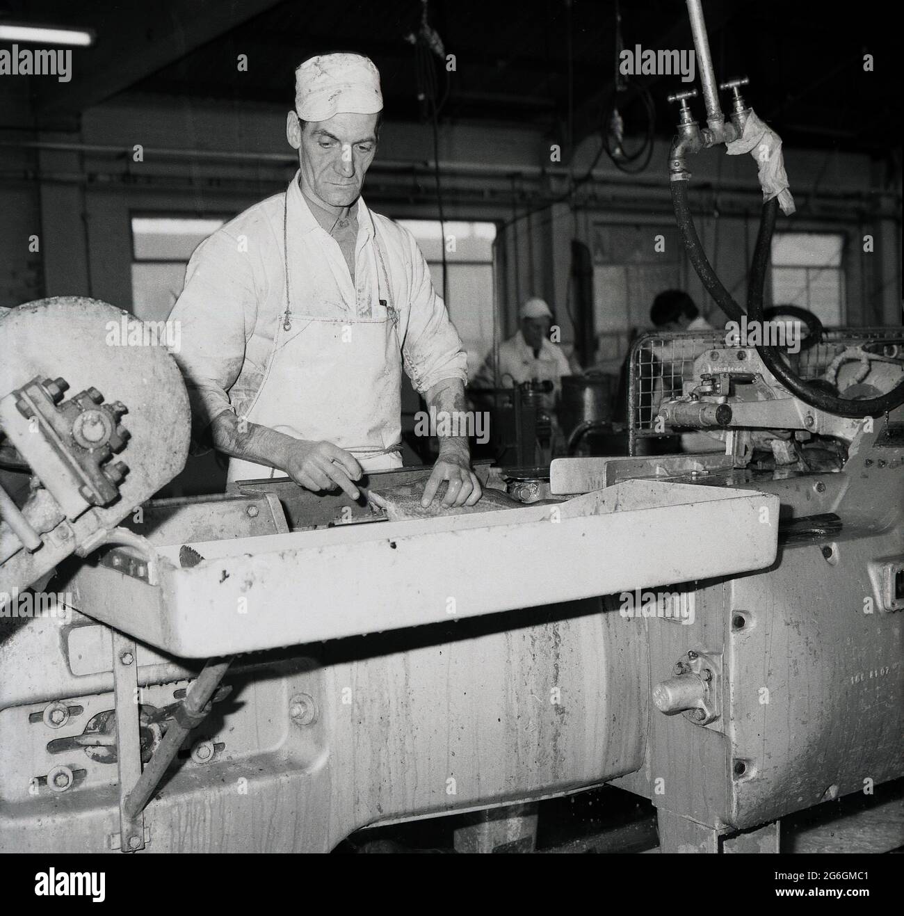 1960s, historical, fish processing factory, a male worker standing at ...